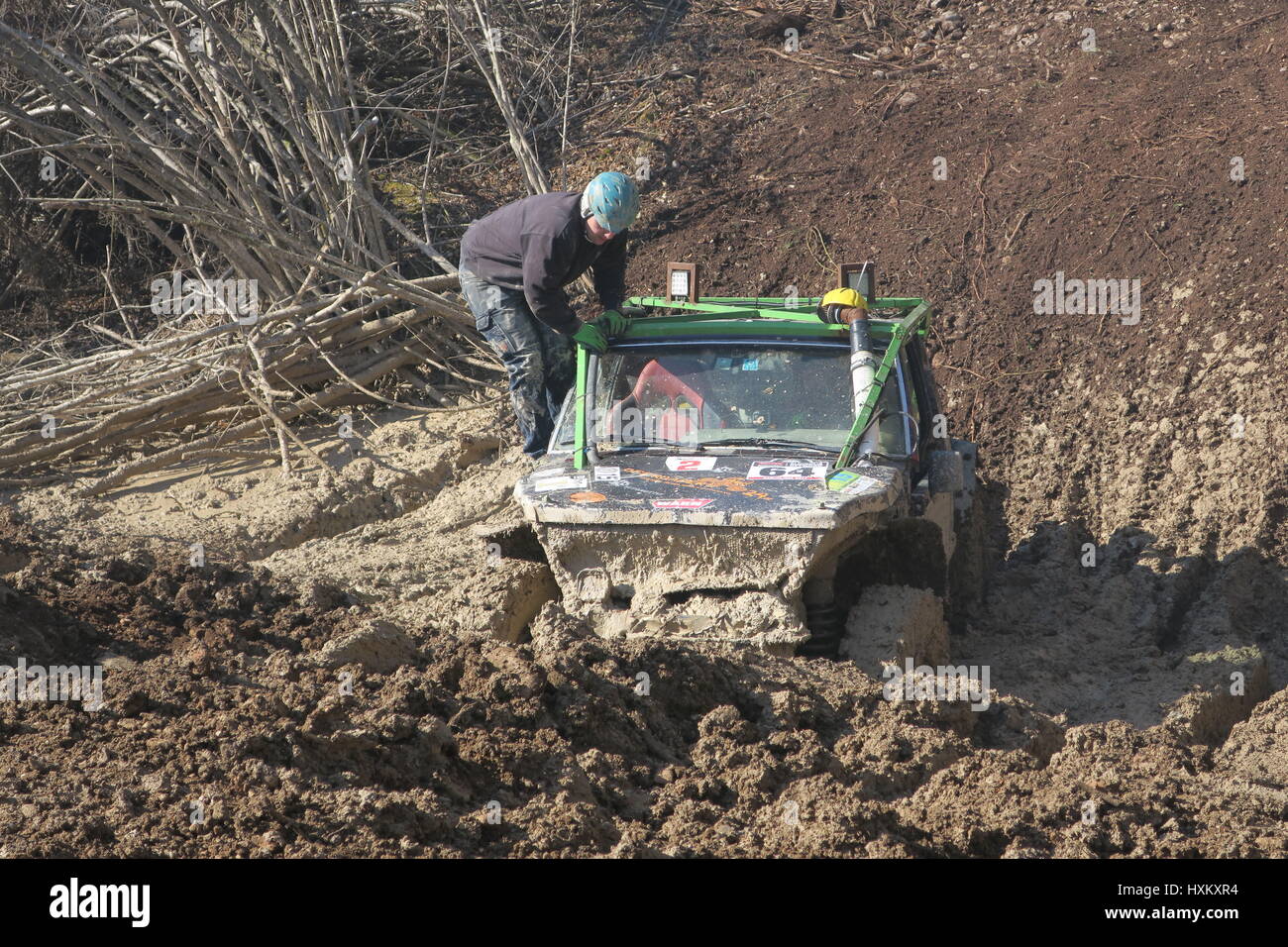 The driver is crawling out of his offroad car to get the steel rope for ... The driver is crawling out of his offroad car to get the steel rope for ...