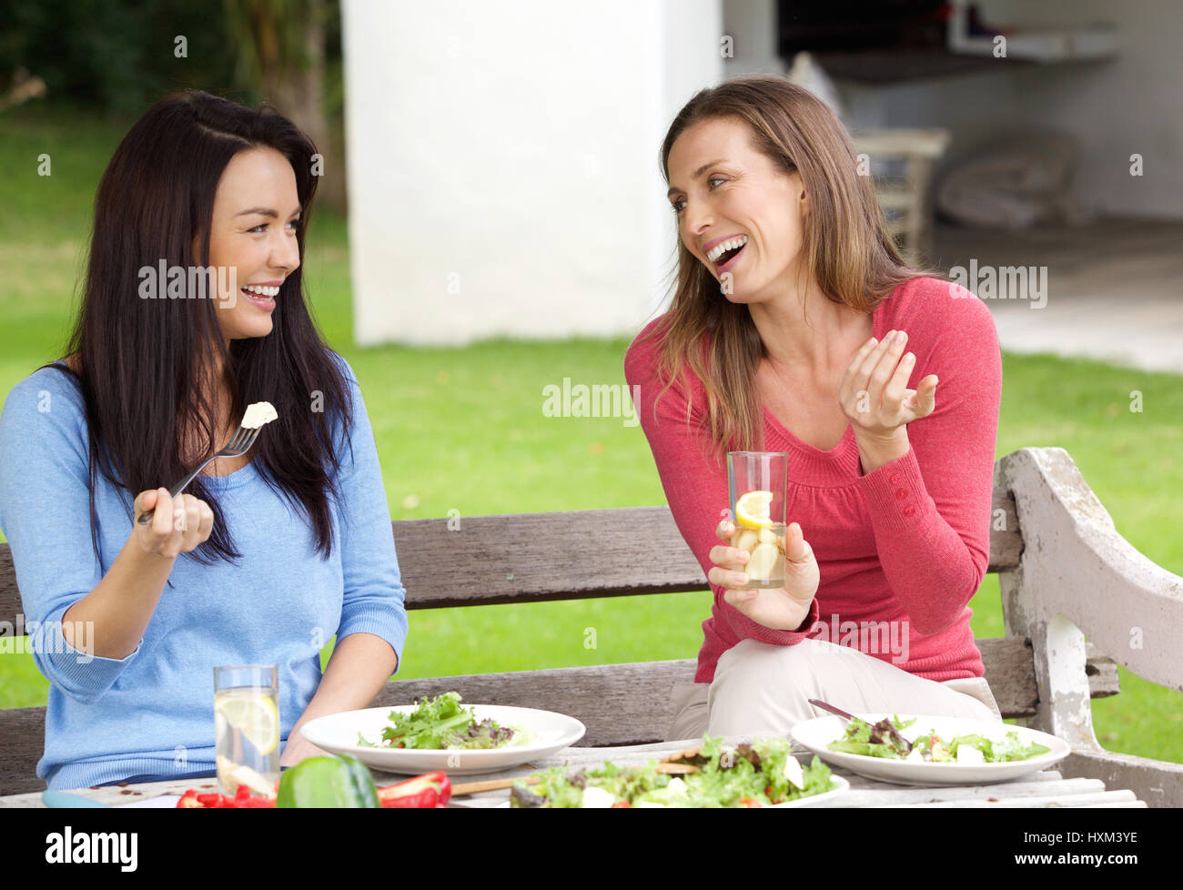 Portrait of two women friends sitting outside in garden having lunch ...