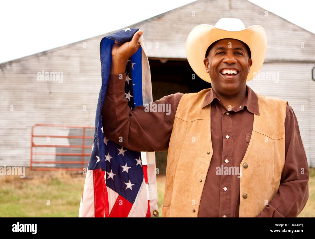 African American cowboy holding an American flag on a farm Stock Photo ...
