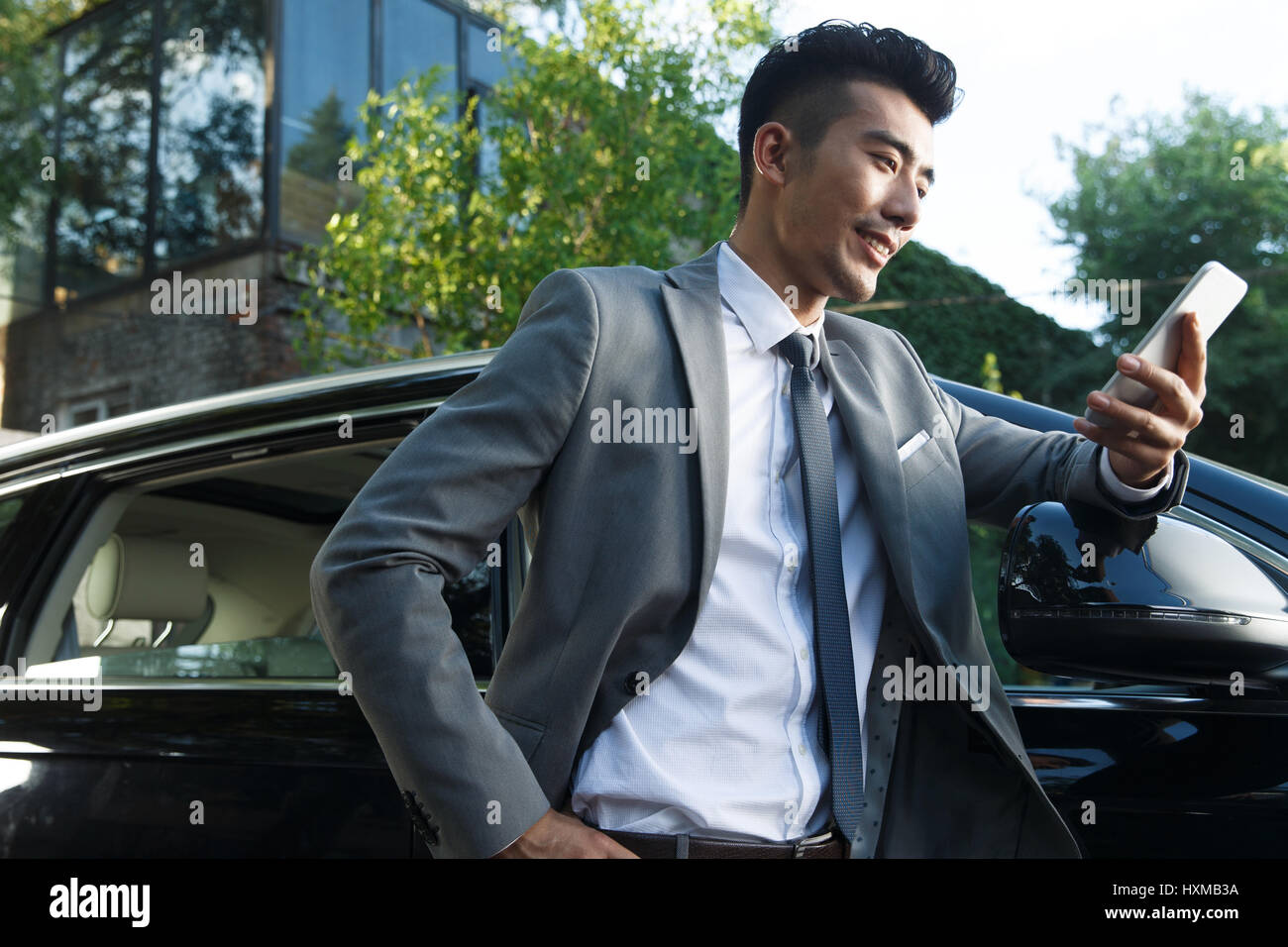 Young man standing by car and using cell phone Stock Photo - Alamy