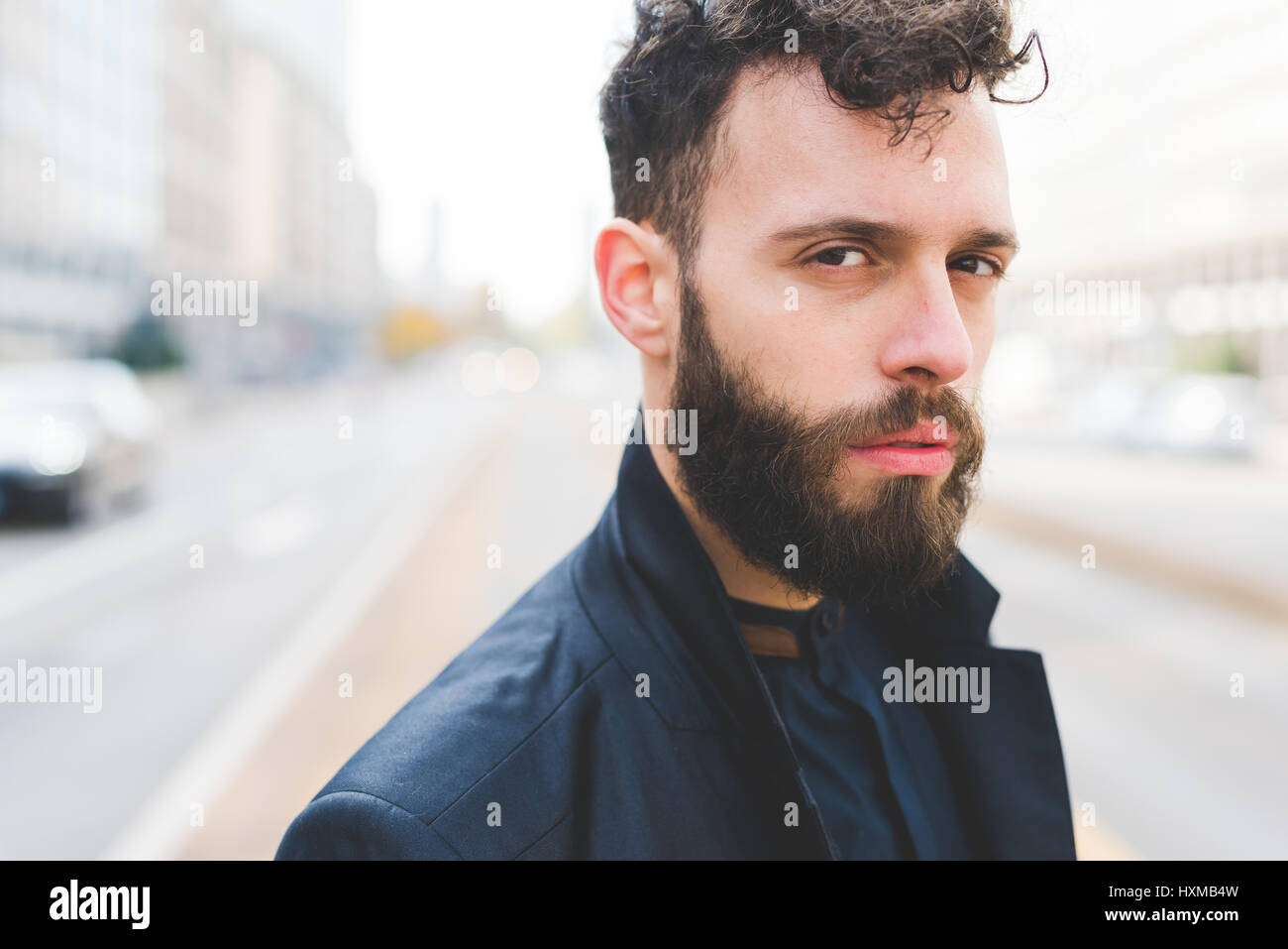 Portrait of young bearded caucasian man outdoor looking camera ...