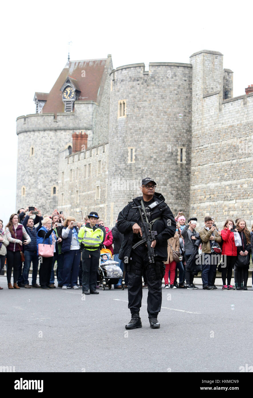 A armed police officer stands with public before the changing of the ...