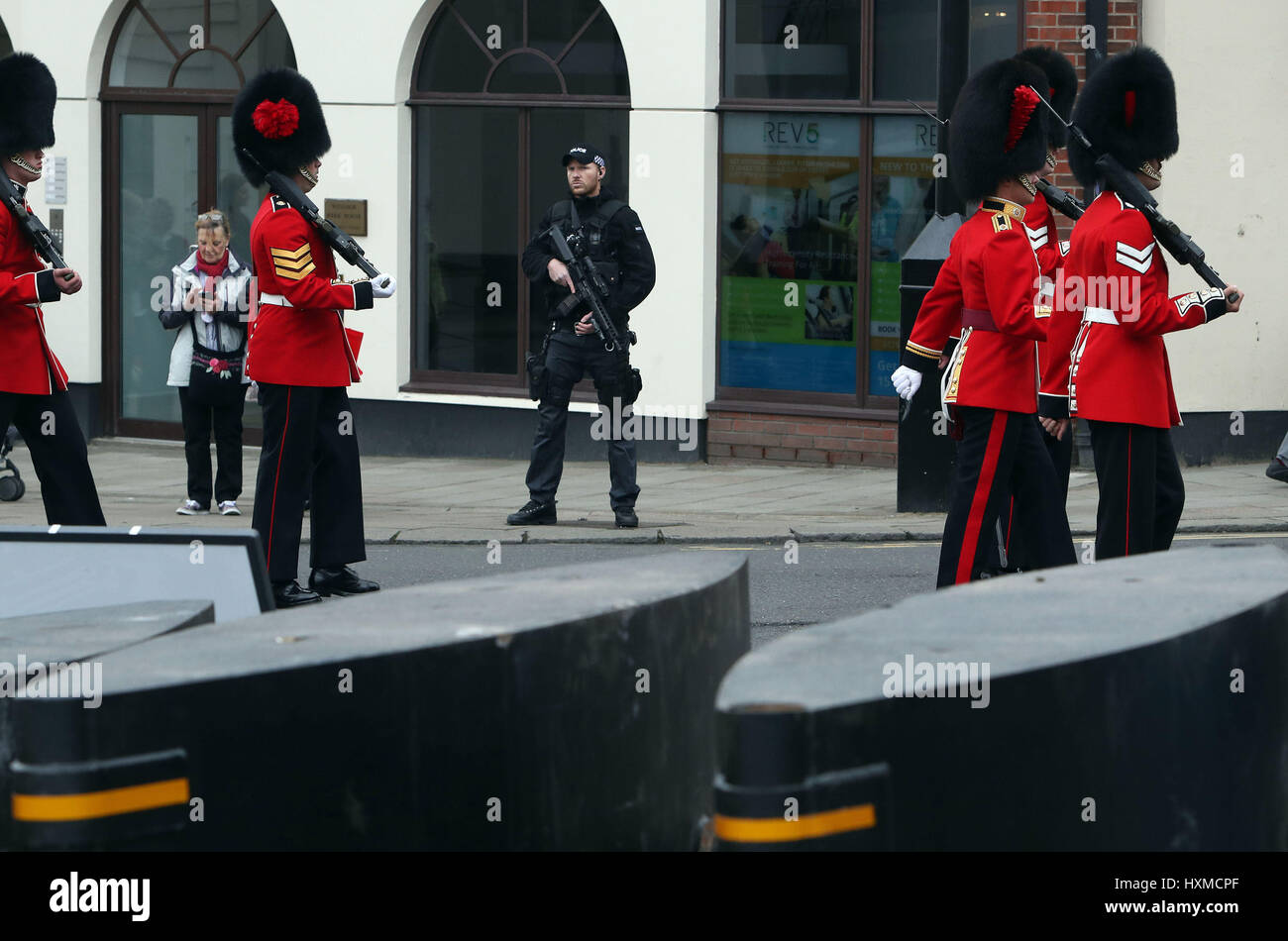 A armed police officer stands with public during the changing of the ...