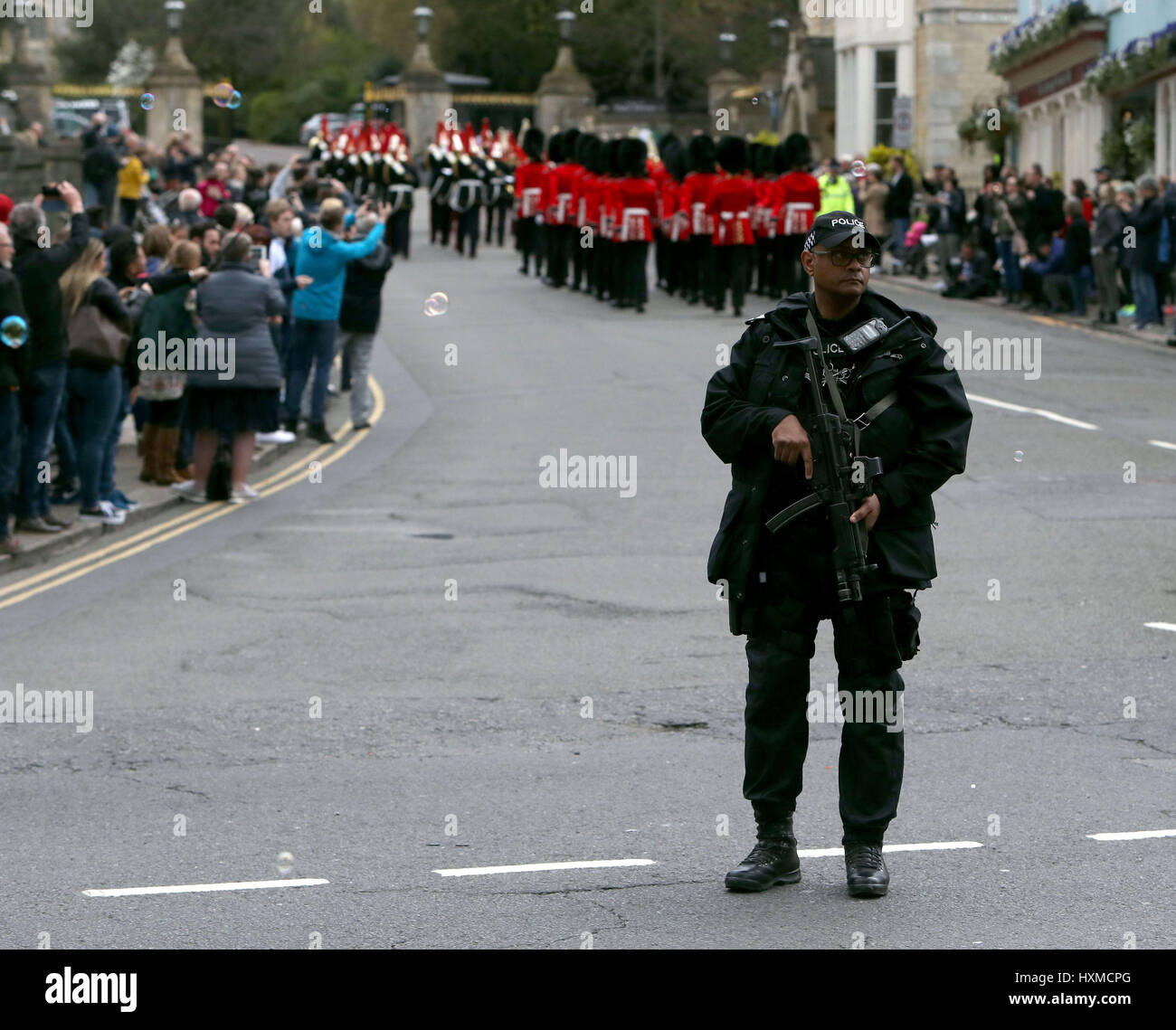 A armed police officer stands with public during the changing of the ...