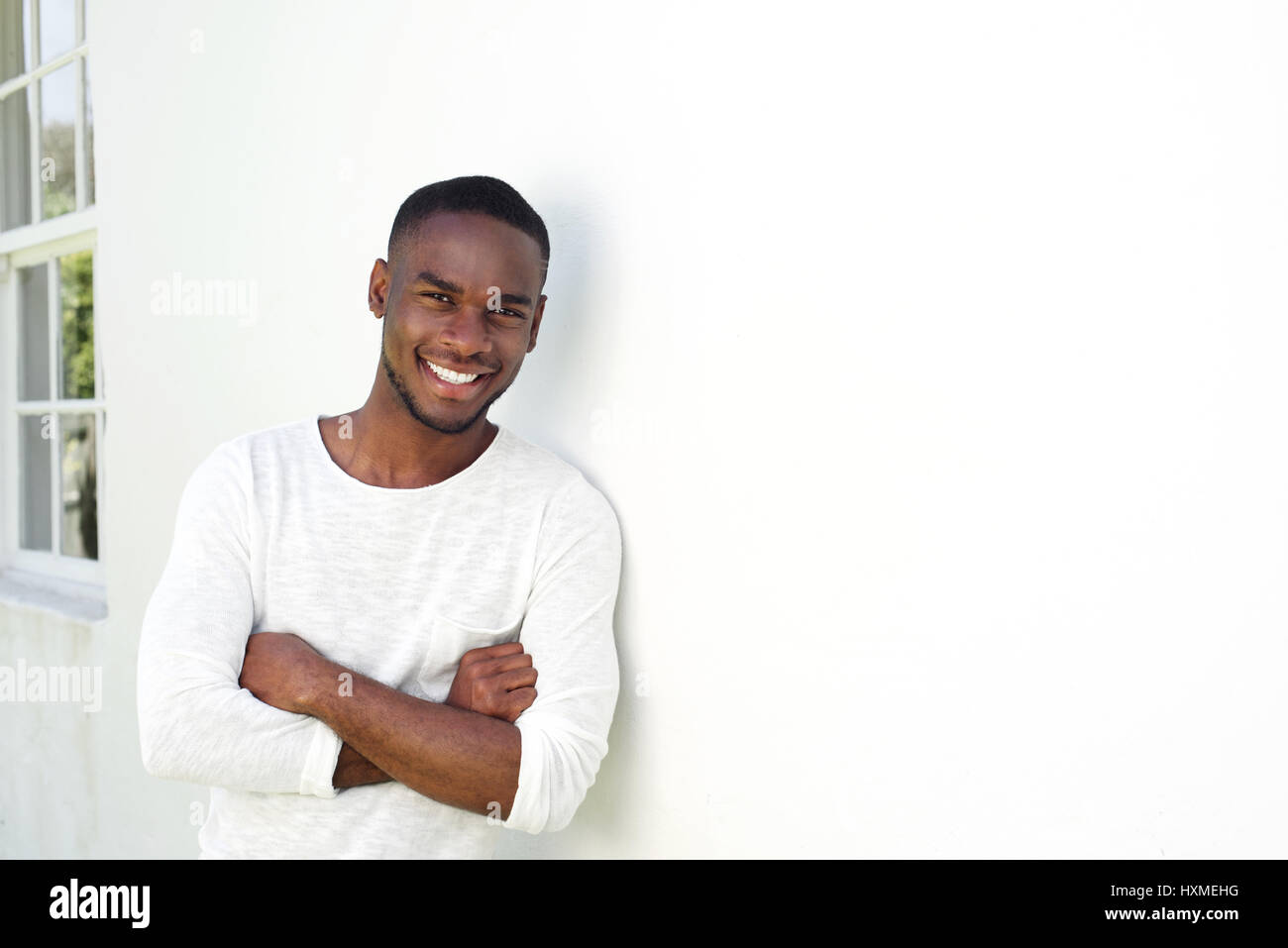 Portrait of handsome young african man standing with his arms crossed ...