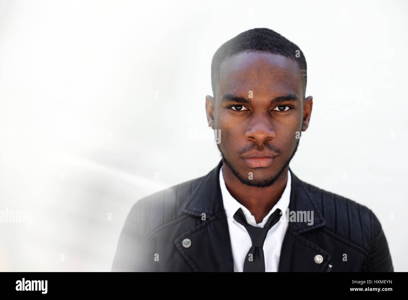 Close up portrait of young male fashion model in leather jacket and tie ...