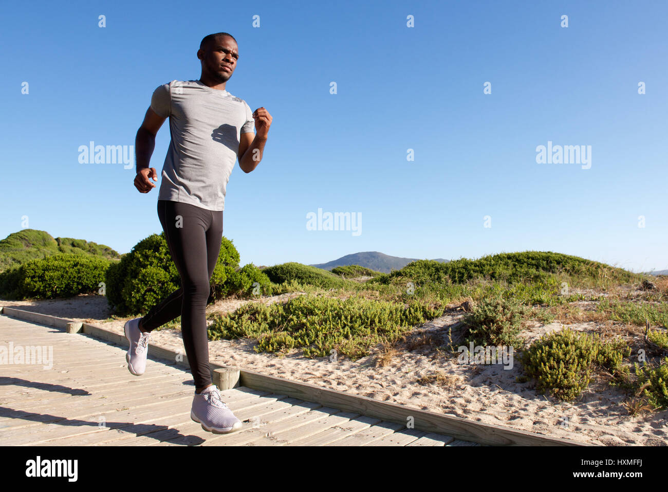 Full length portrait of fitness male model running on the boardwalk at ...