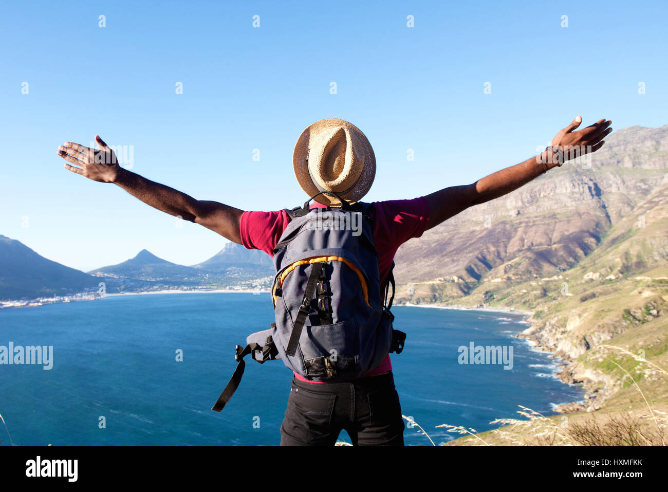 Rear view portrait of young man with backpack standing on a mountain ...