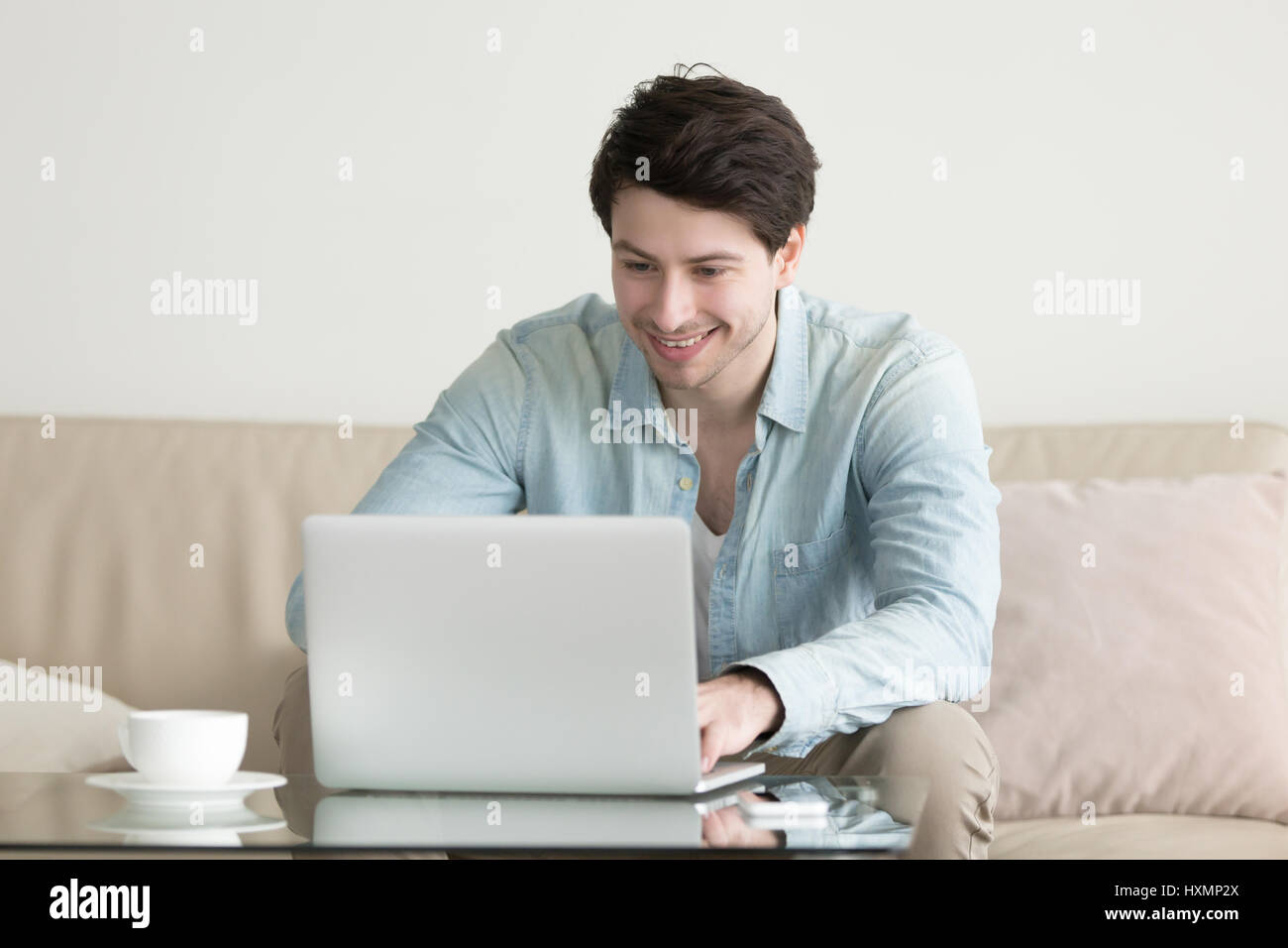 Young man smiling, chatting, working online with laptop computer Stock ...