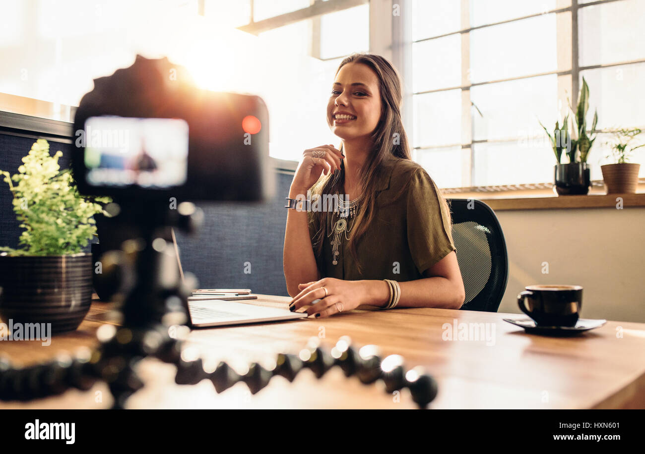 Young woman recording video for her vlog on a digital camera mounted on ...