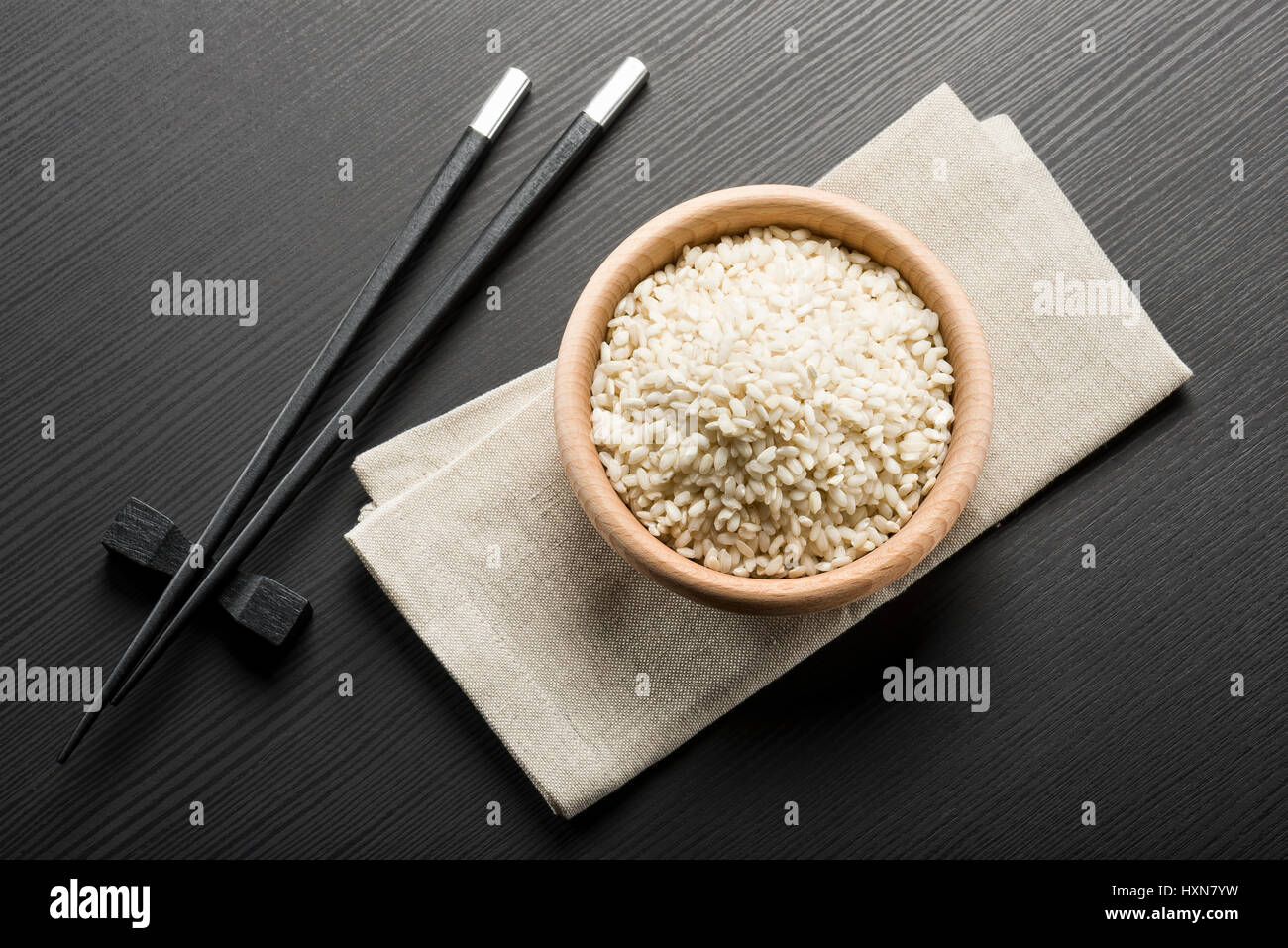 wooden bowl with rice and japanese chopsticks on black wooden table ...