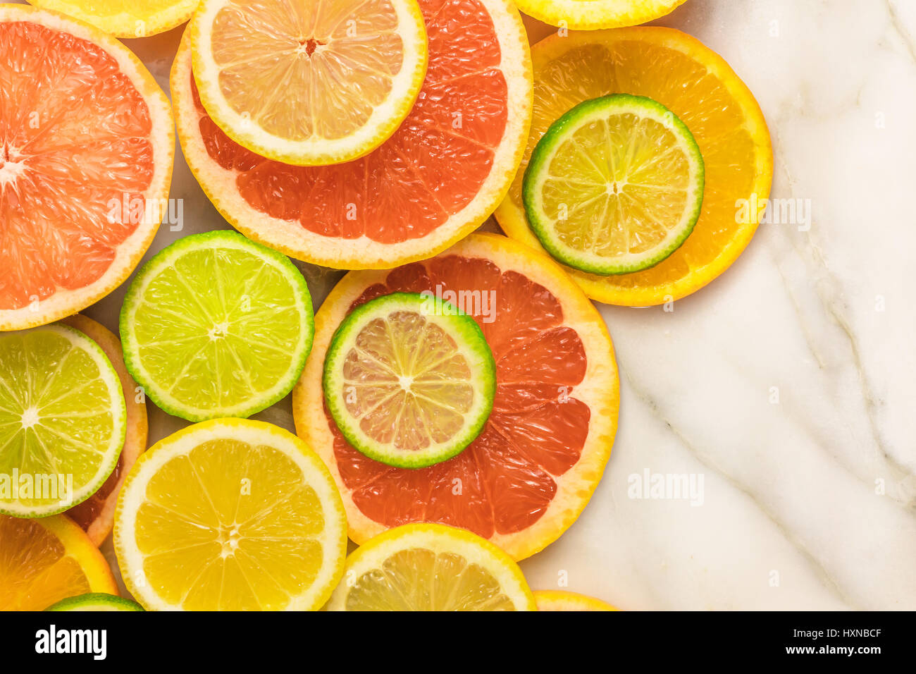 Vibrant juicy citrus fruits on a white marble texture with copy space ...