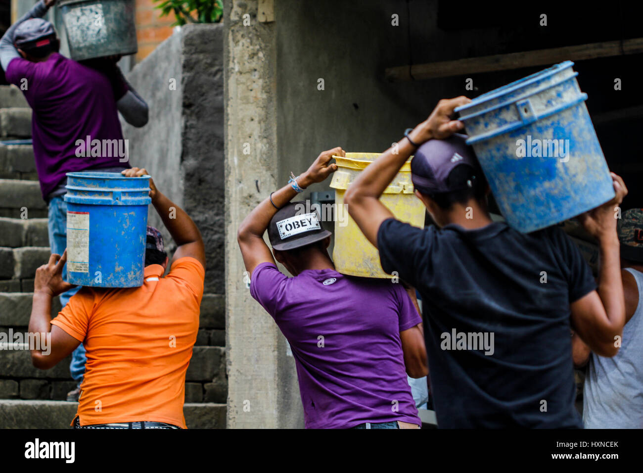 People are carrying heavy big buckets with some material inside Stock ...
