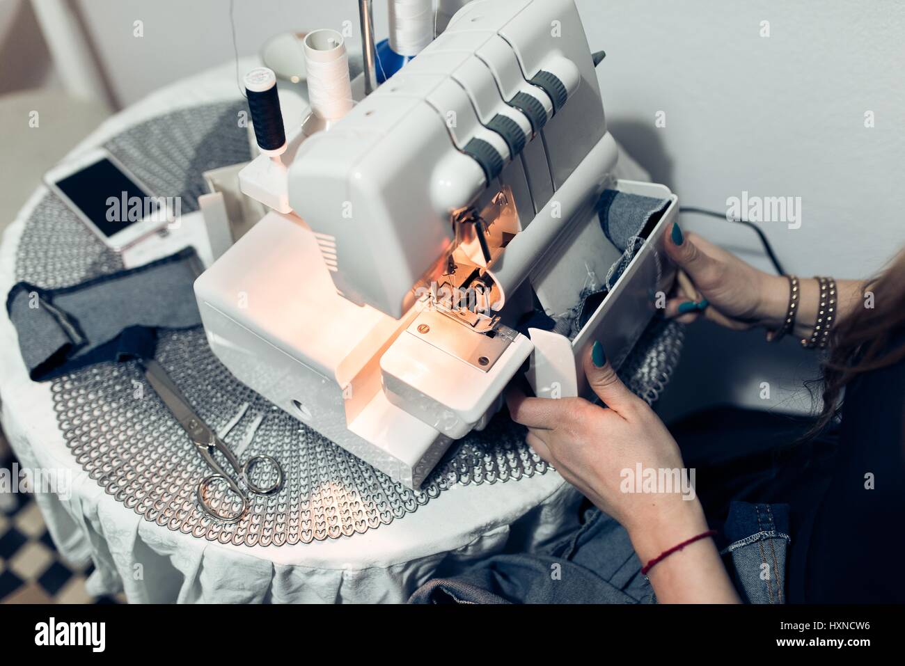 White modern overlock machine, woman hitting a piece of cloth on a ...