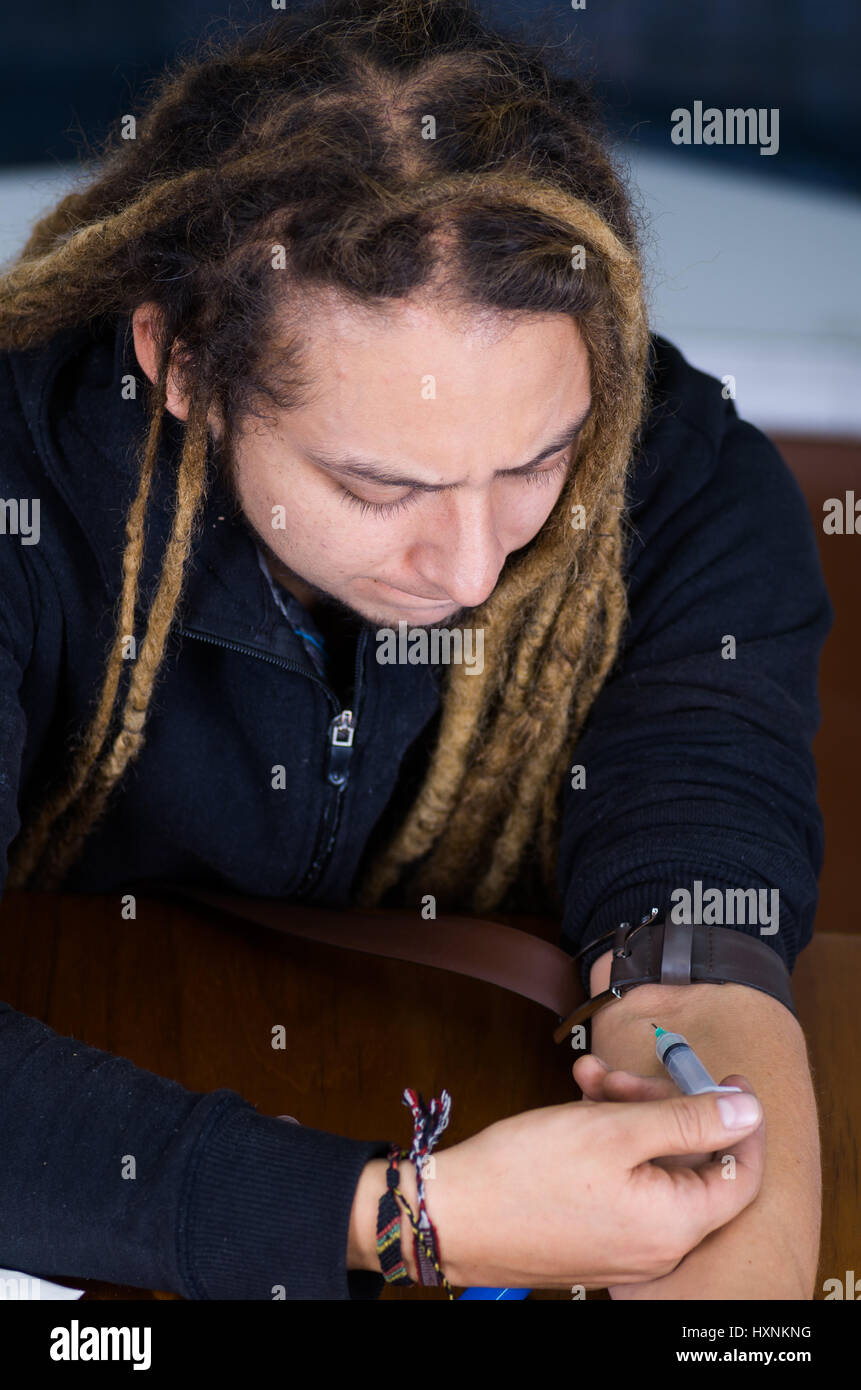 Man with drug addiction sitting down injecting narcotics into arm using ...
