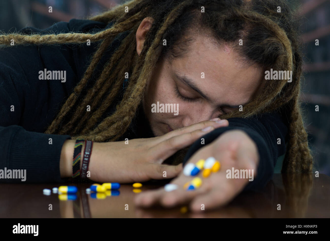 Man lying over table with dopey facial expression, colorful pills lying ...
