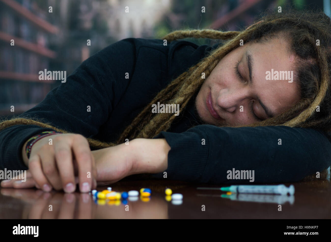Man lying over table with dopey facial expression, colorful pills and ...