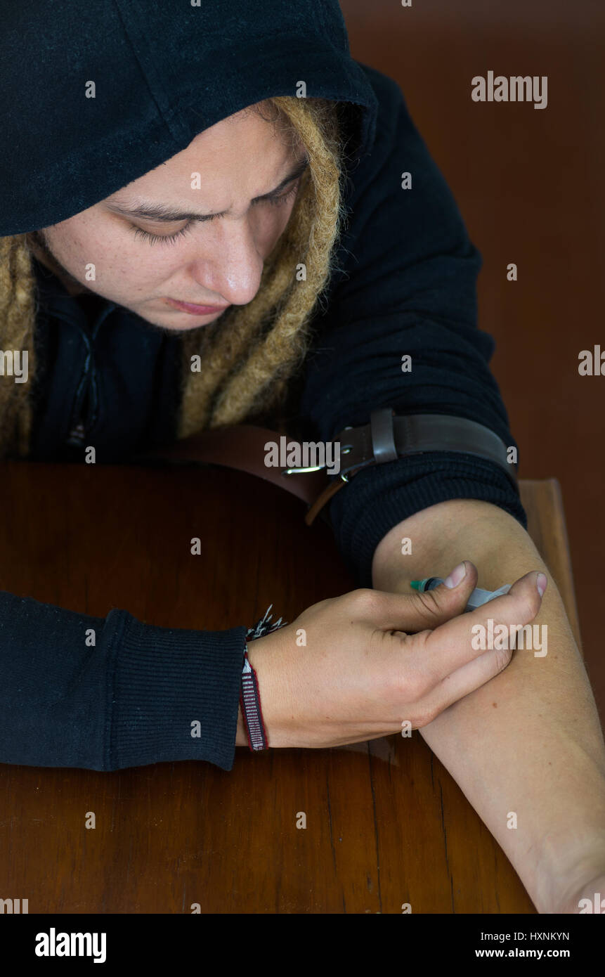 Man with drug addiction sitting down injecting narcotics into arm using ...