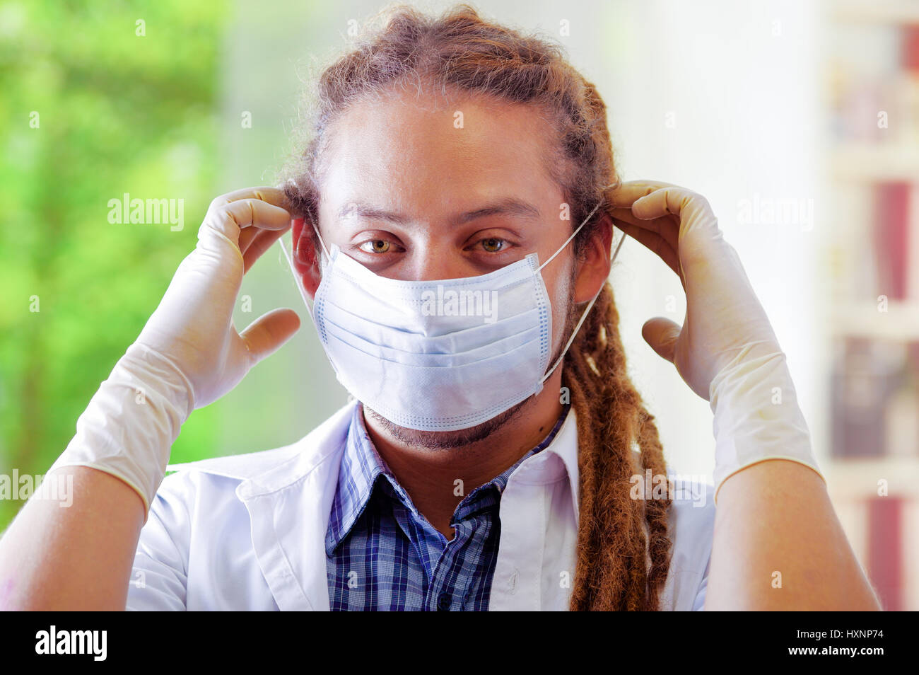 Young doctor with long dread locks posing for camera, adjusting facial ...