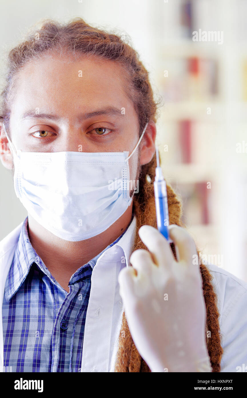 Young doctor with long dread locks posing for camera holding syringe ...