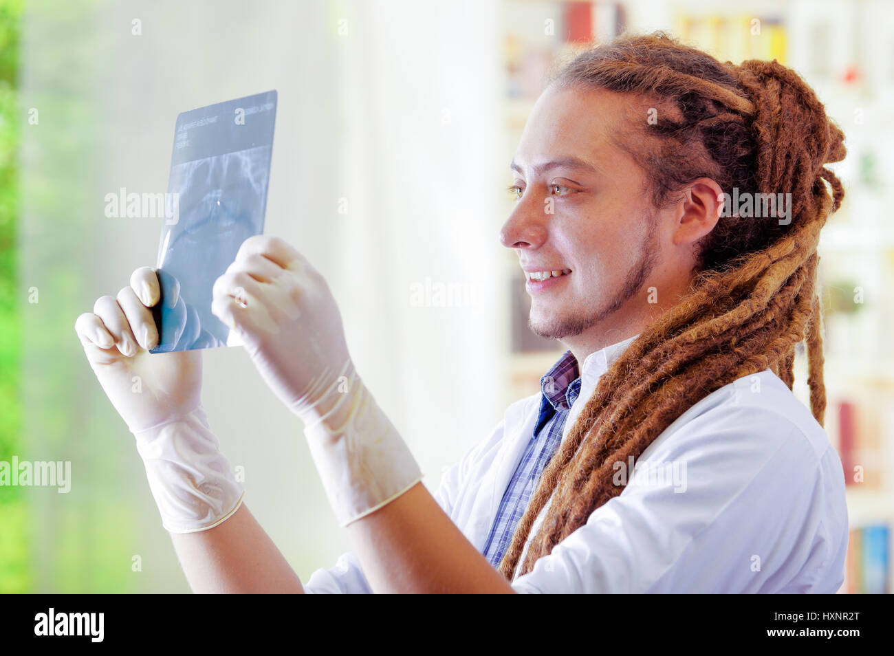 Young doctor with long dread locks posing for camera, holding up x ray ...