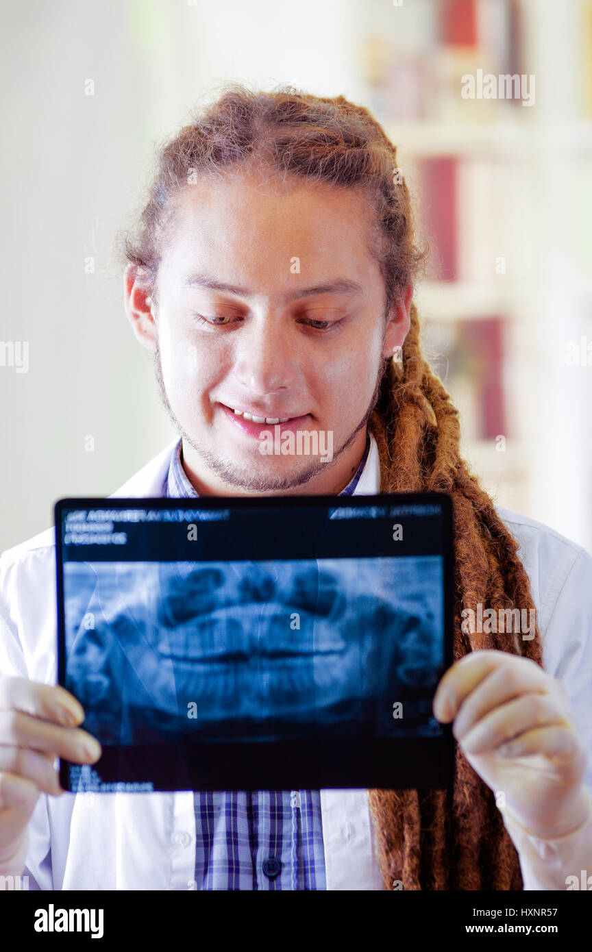 Young doctor with long dread locks posing for camera, holding up x ray ...