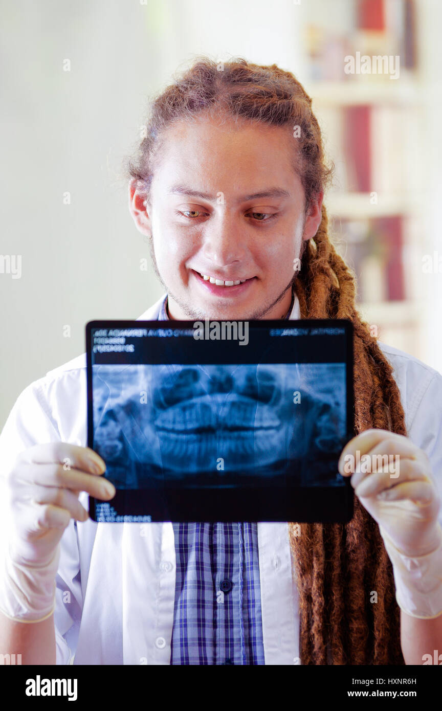 Young doctor with long dread locks posing for camera, holding up x ray ...