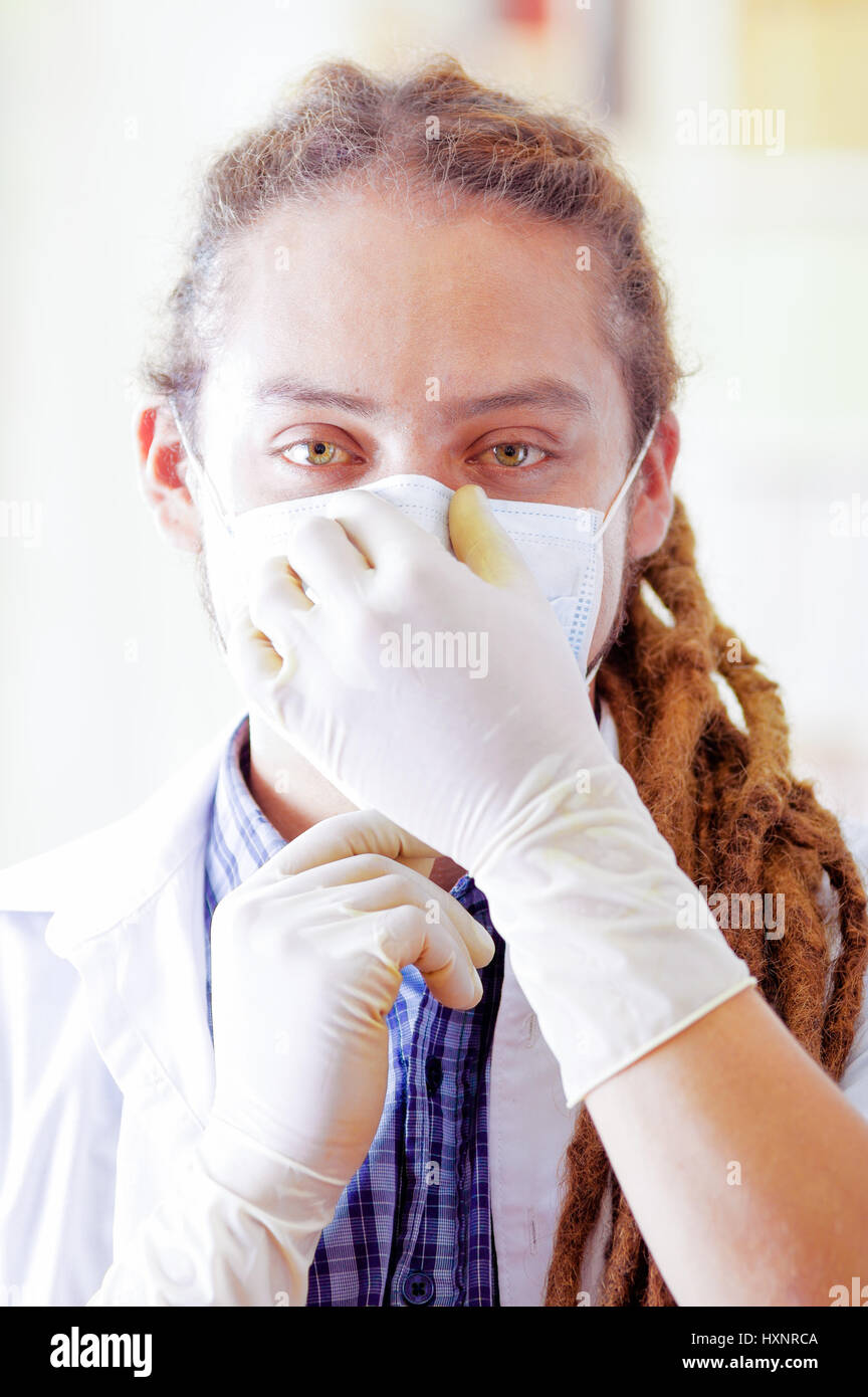 Young doctor with long dread locks posing for camera, adjusting facial ...