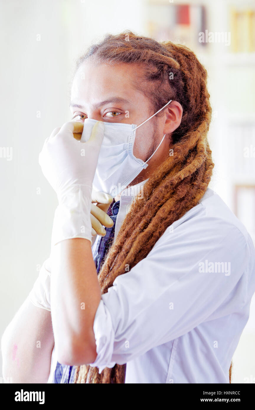 Young doctor with long dread locks posing for camera, adjusting facial ...