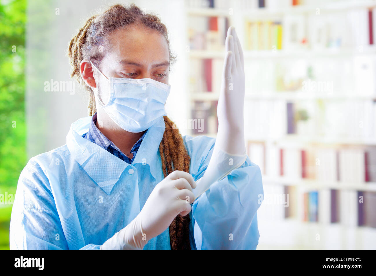 Young doctor with long dread locks posing for camera while putting on ...