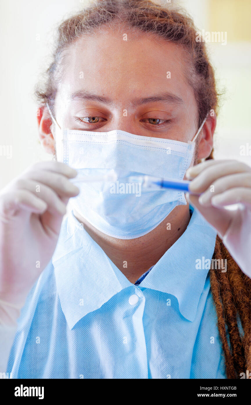 Young doctor with long dread locks posing for camera preparing syringe ...