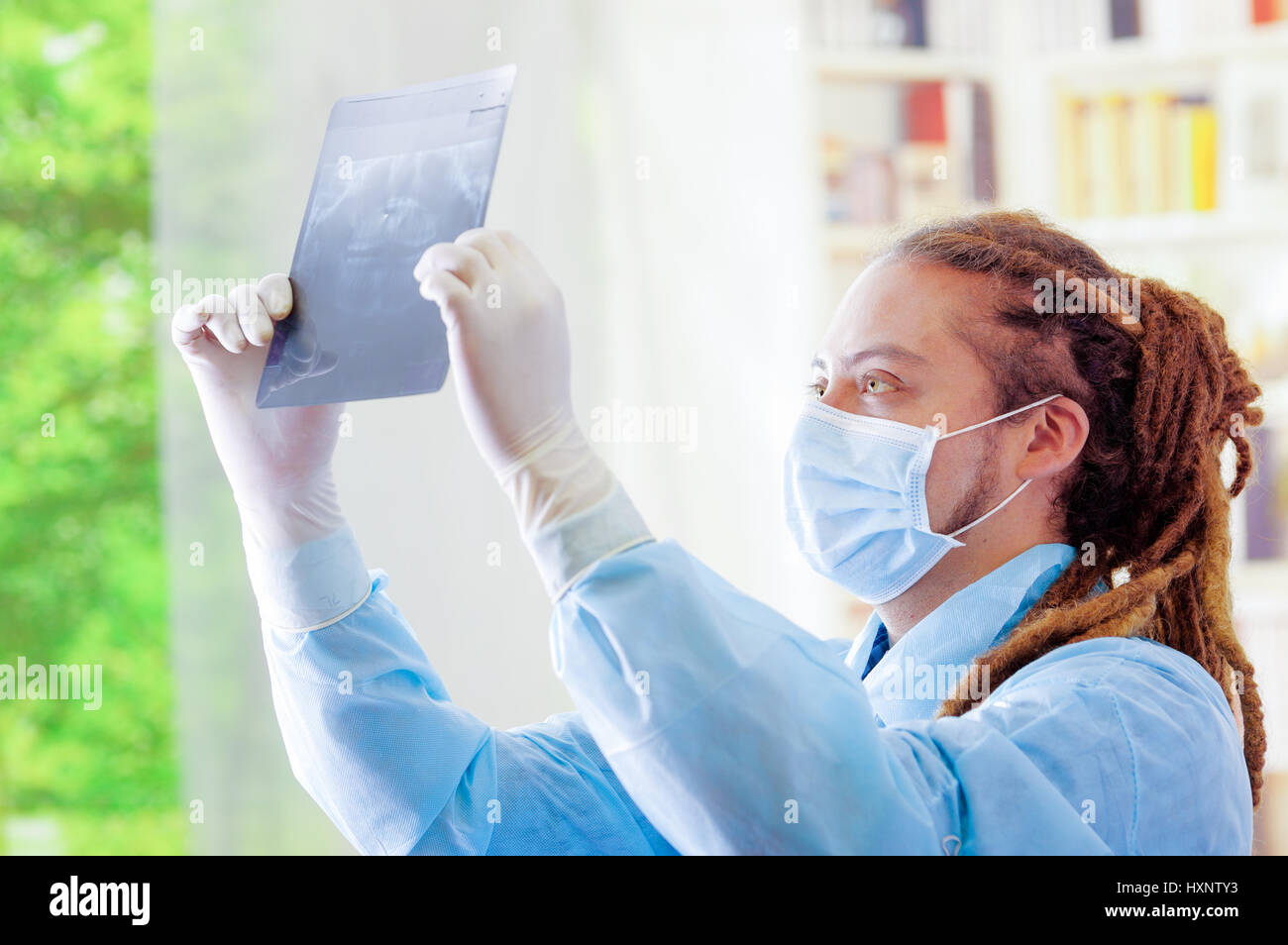 Young doctor with long dread locks posing for camera, holding up x ray ...