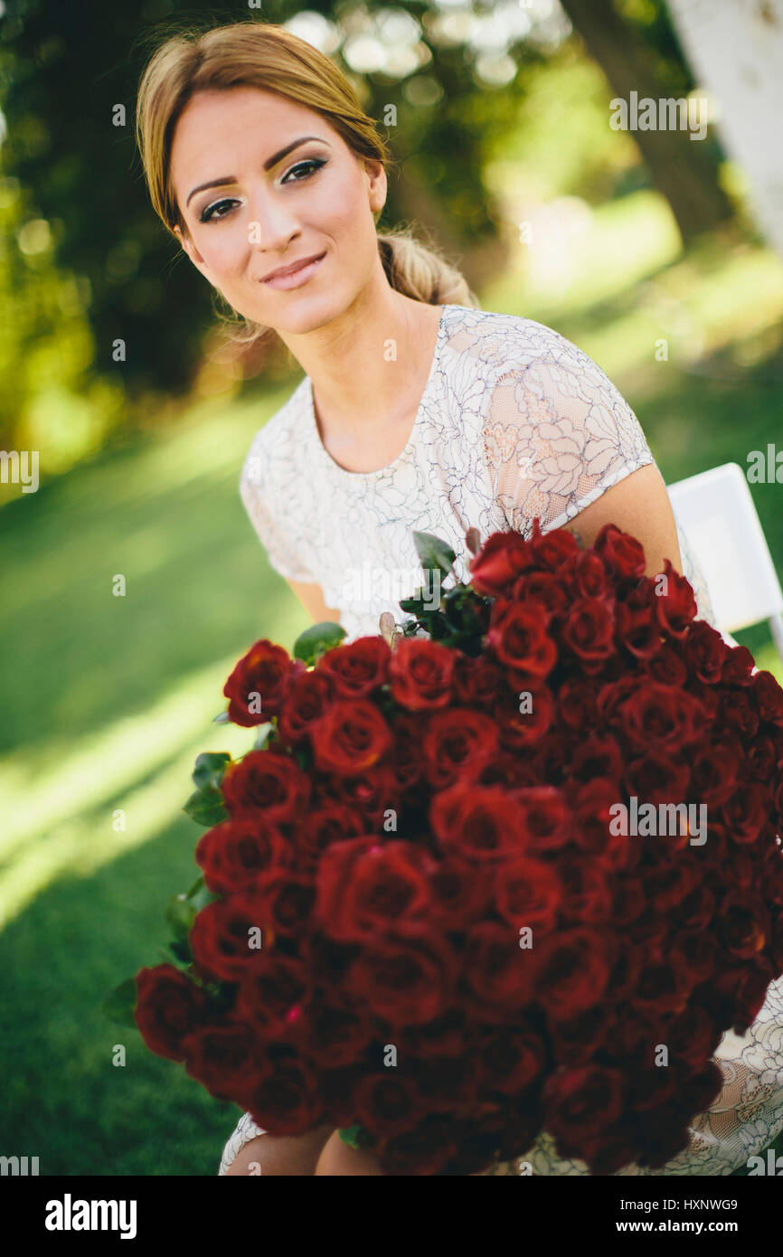 Young woman with a bouquet of red roses sitting outside Stock Photo - Alamy