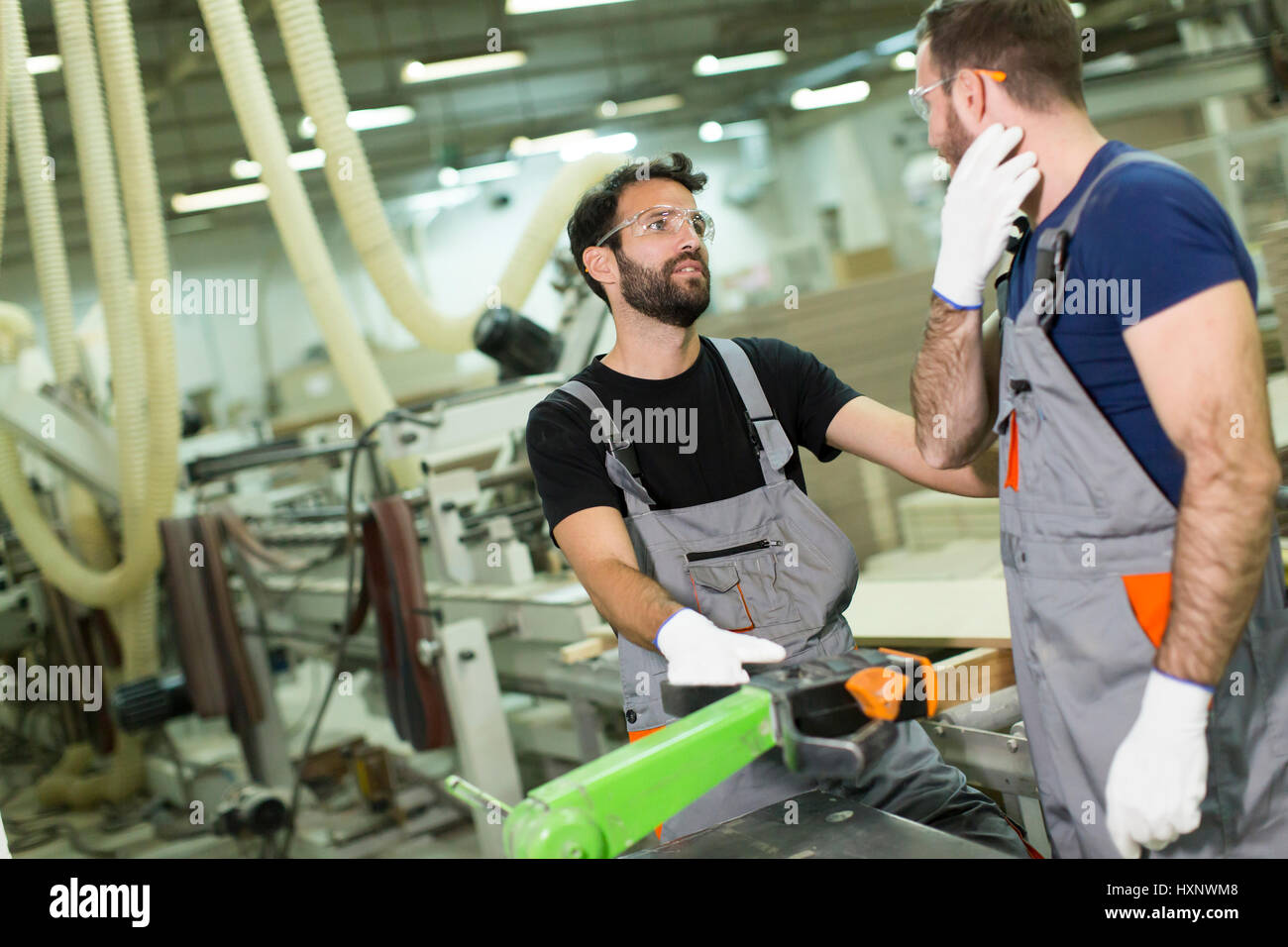 Two handsome young men working in lumber workshop Stock Photo - Alamy