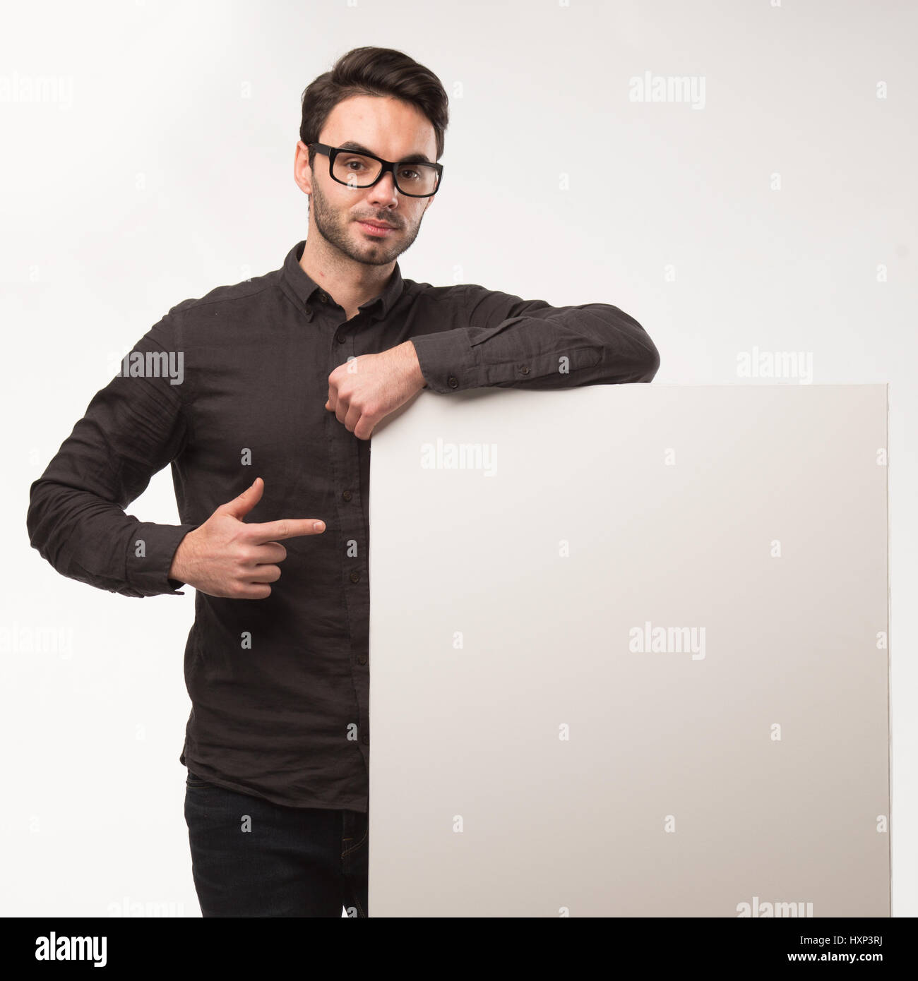 Young happy man showing presentation, pointing on placard over gray ...