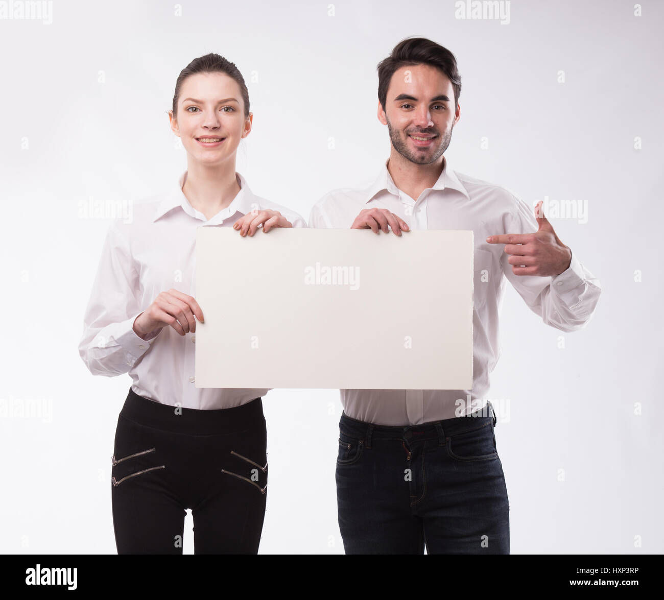 Young happy couple showing presentation pointing on placard over gray ...