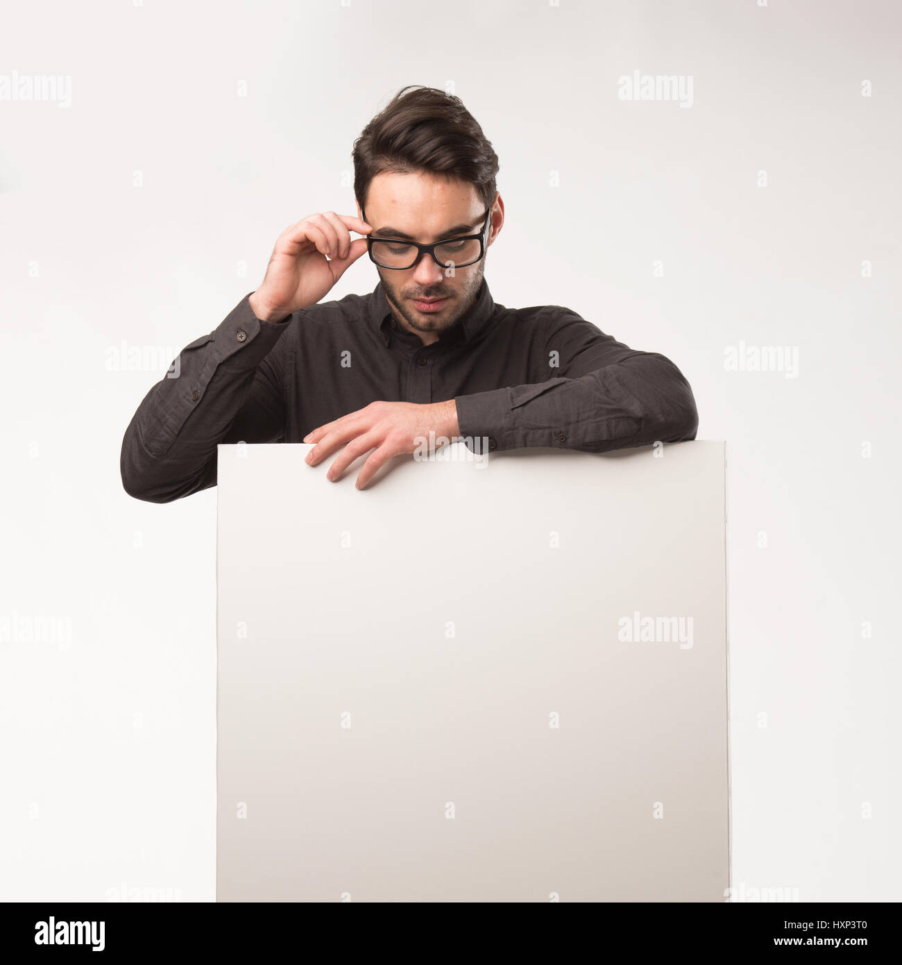 Young happy man showing presentation, pointing on placard over gray ...