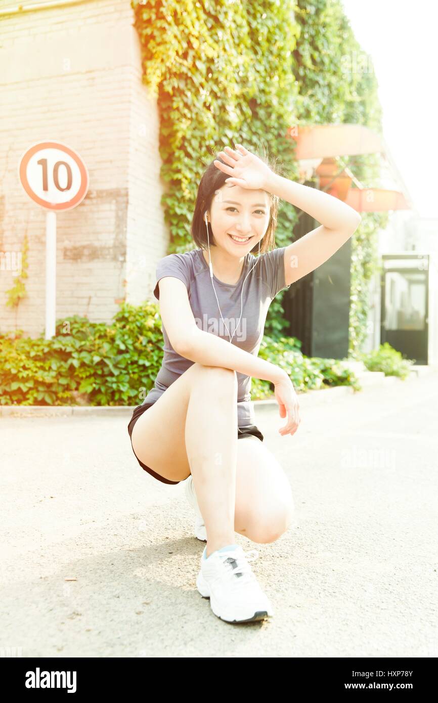 Young woman squatting with one knee down Stock Photo - Alamy