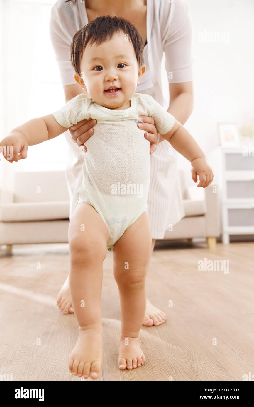 Mother helping baby boy learn to walk Stock Photo - Alamy