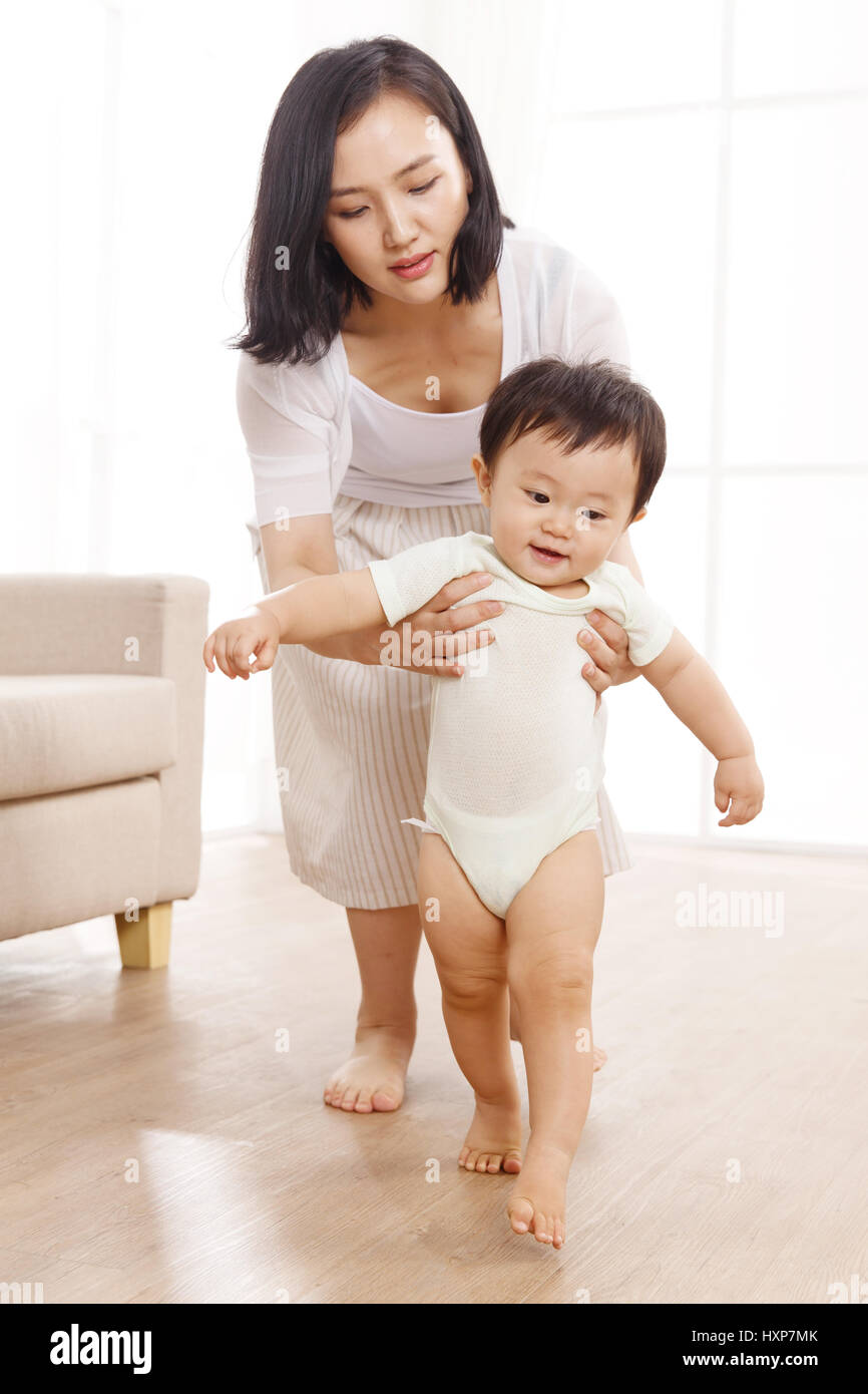 Mother helping baby boy learn to walk Stock Photo - Alamy