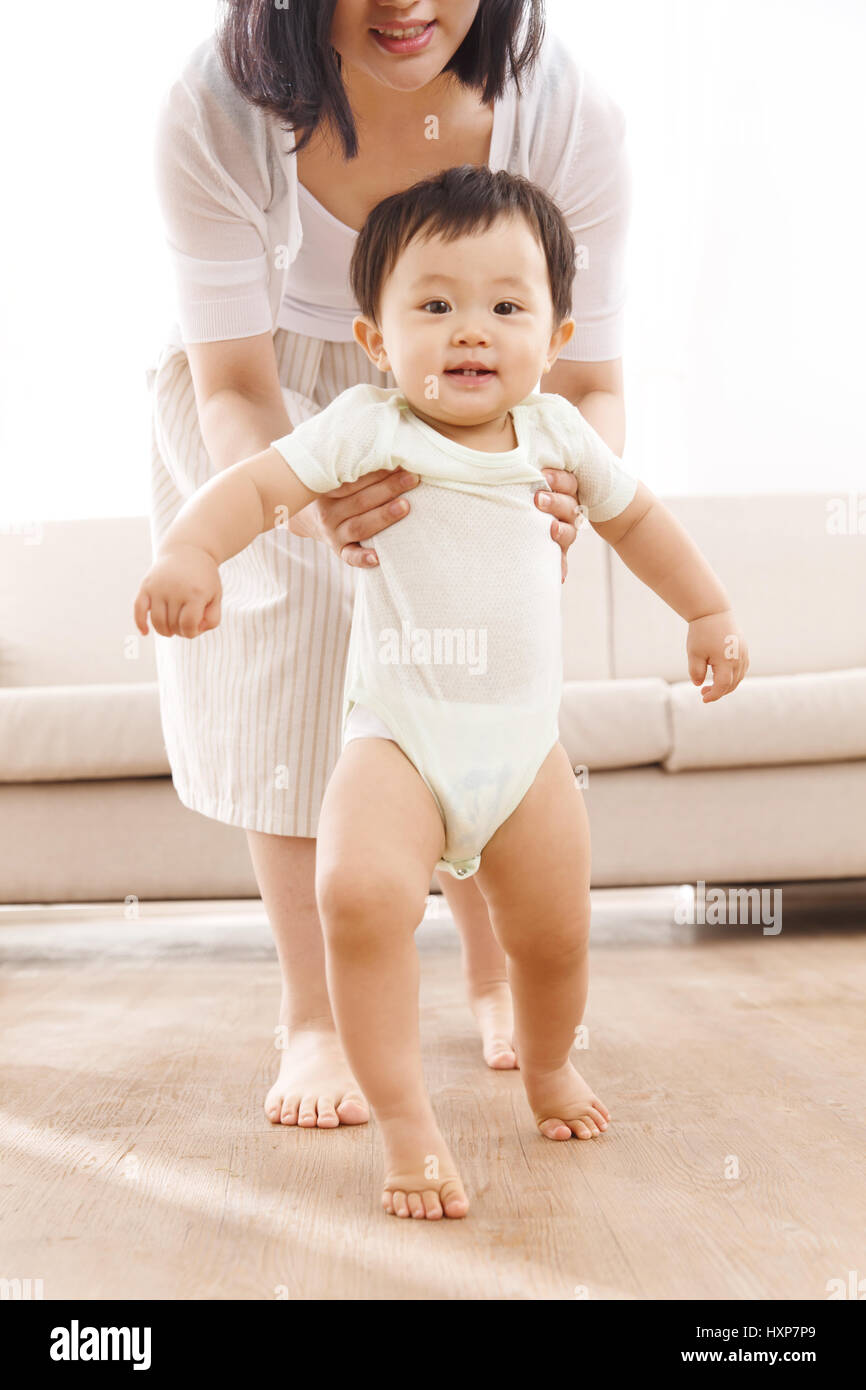 Mother helping baby boy learn to walk Stock Photo - Alamy