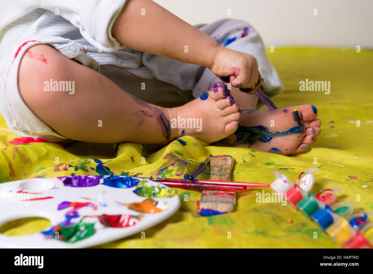 Little child painting feet using colorful paints Stock Photo - Alamy