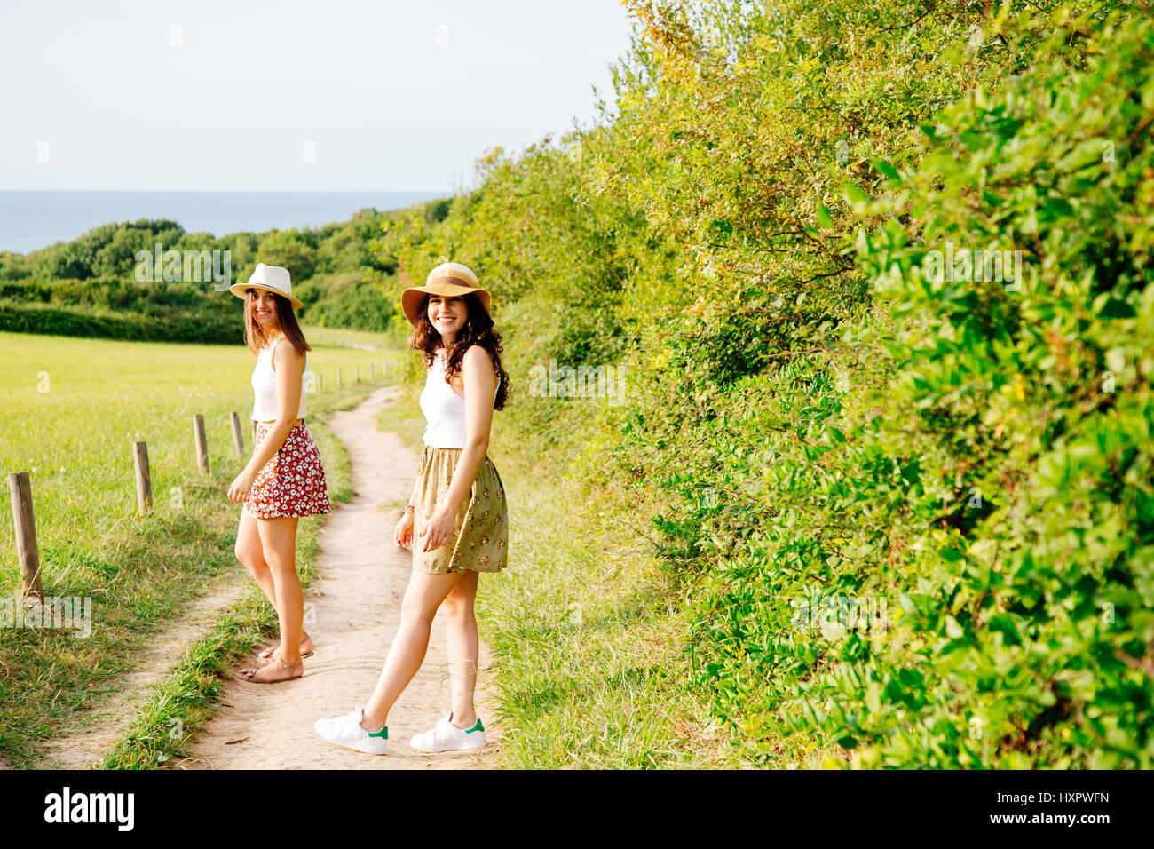 Portrait of two beautiful female friends with hats strolling in the ...