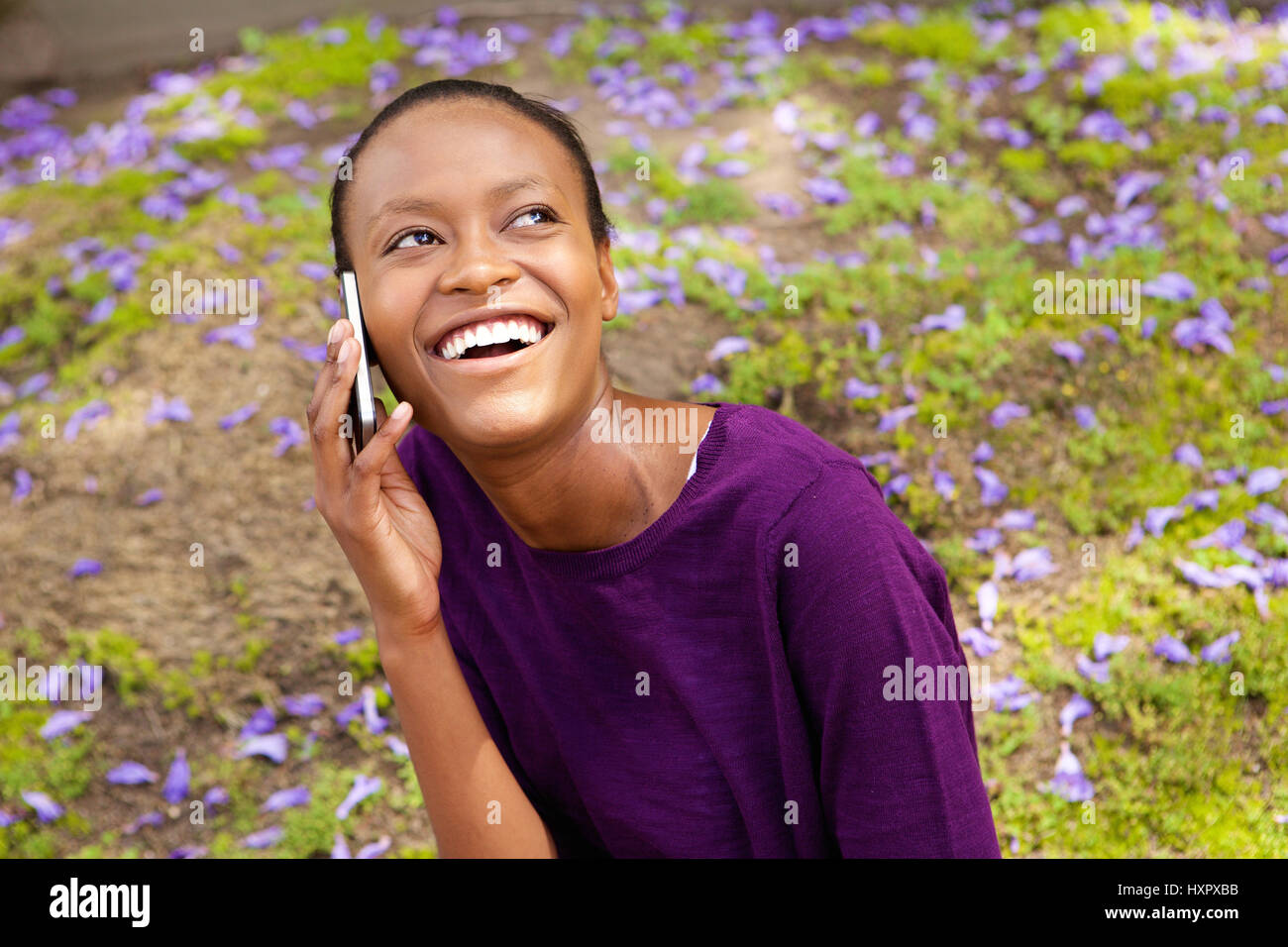 Close up portrait of attractive young black woman sitting outdoors ...