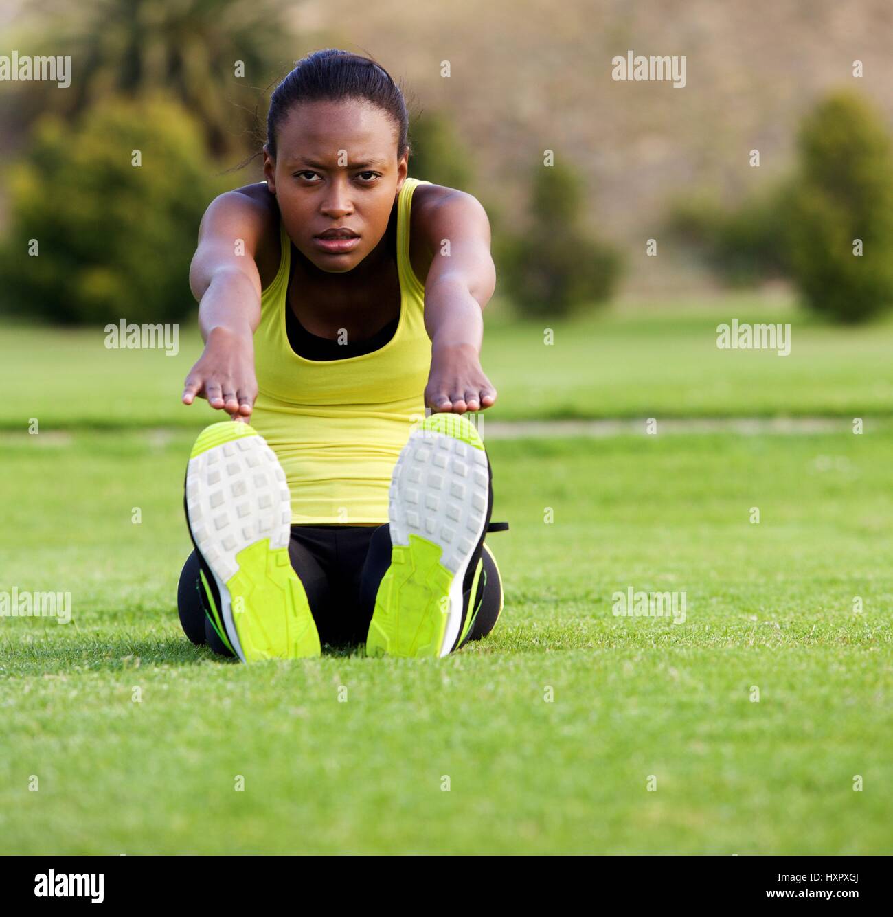 Portrait of a fit young woman stretching toe touch exercise in the park ...