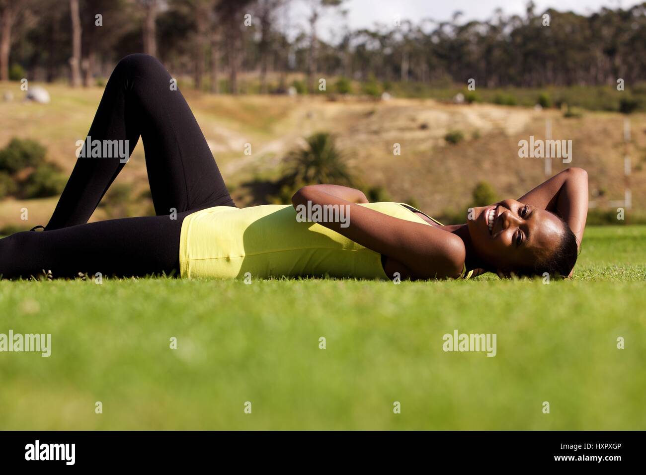 Side portrait of tired fit woman relaxing on grass at park Stock Photo ...