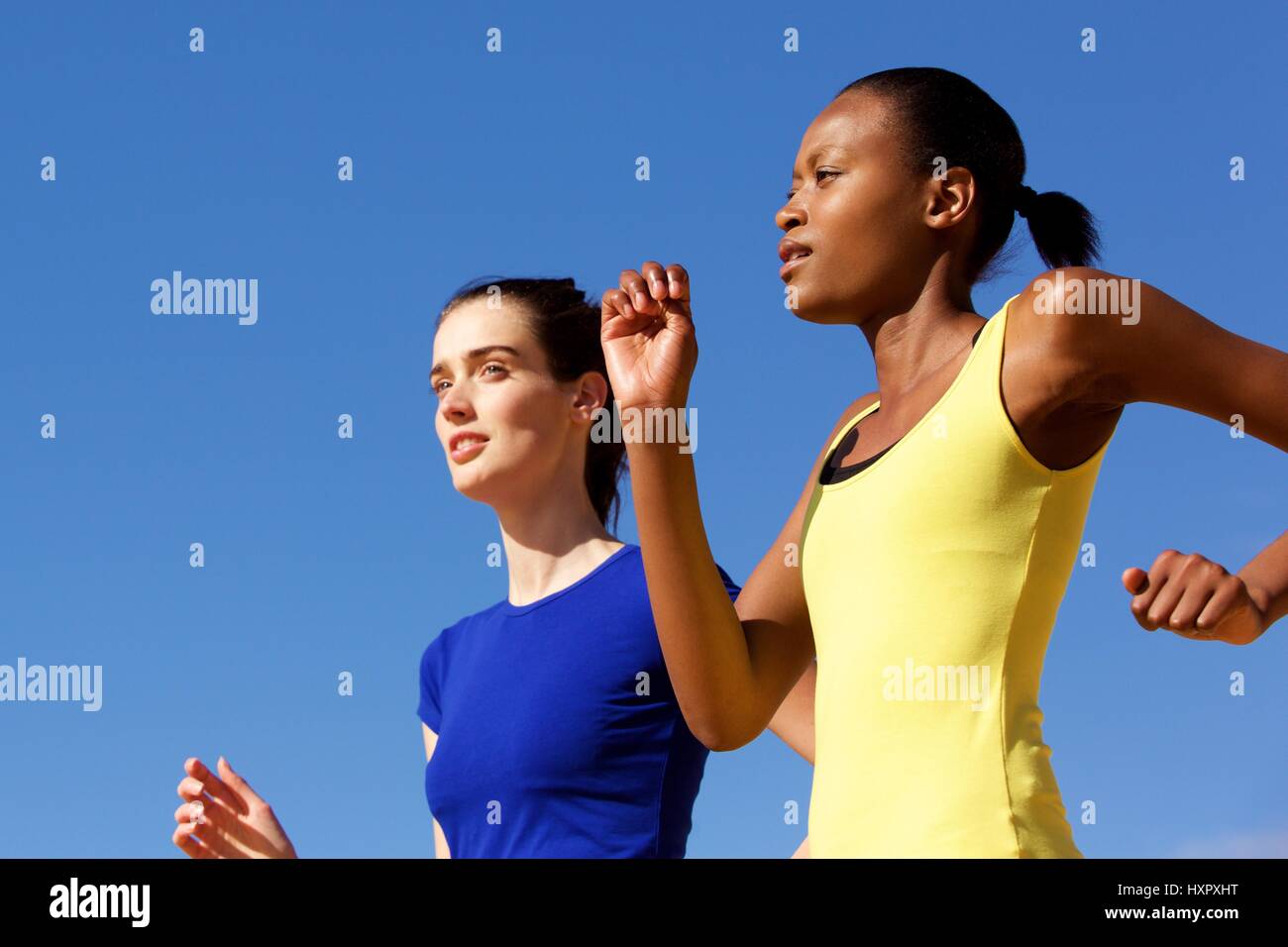 Close up portrait of two young women jogging together outdoors Stock ...