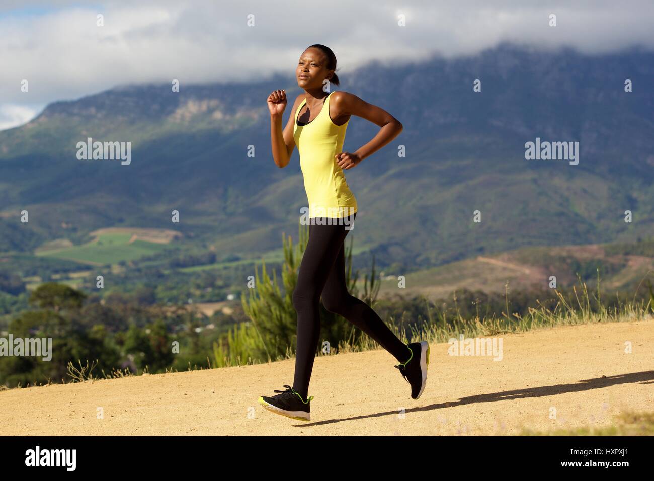 Full length side portrait of fit young african woman jogging outdoors ...