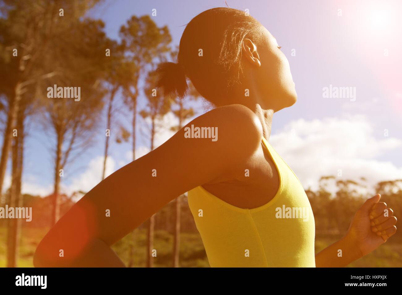 Side portrait of fit african woman running outdoors on a sunny day ...