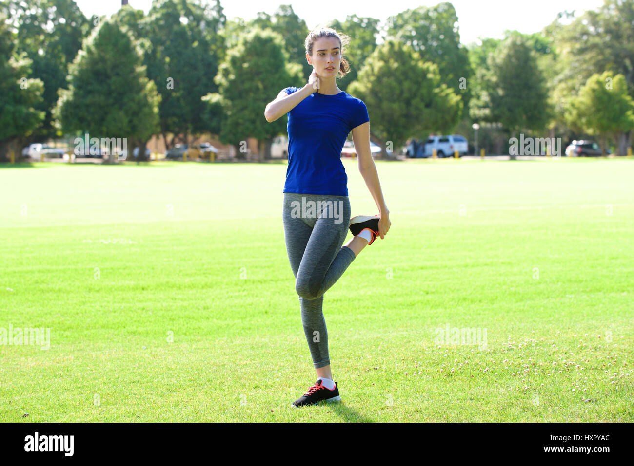 Full length portrait of sporty woman stretching in field Stock Photo ...